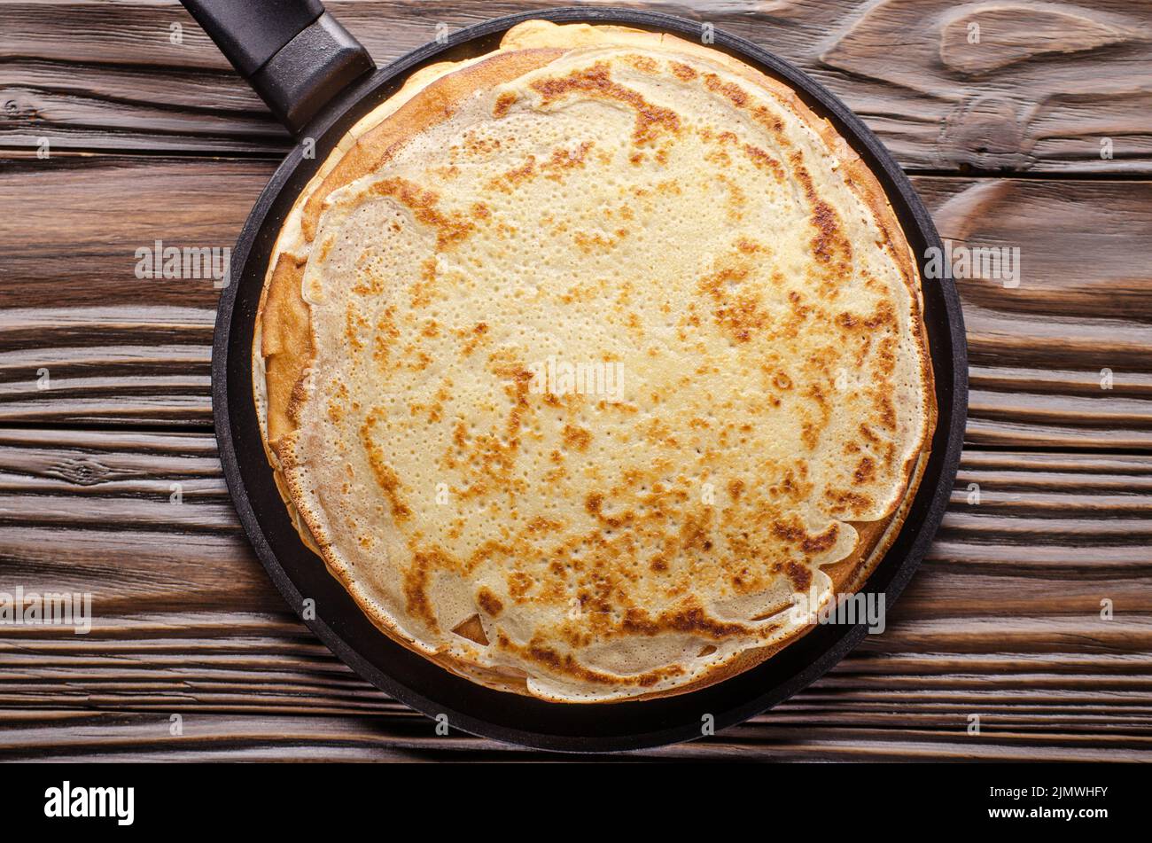 Stack of French crepes in frying pan on wooden kitchen table Stock ...
