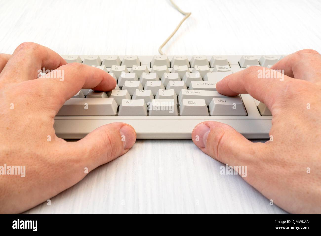 Hands typing on white keyboard with cable Stock Photo - Alamy