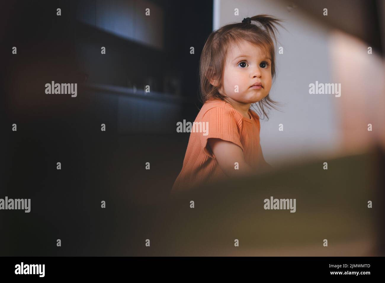 View from behind the chair of a baby girl looking into the distance ...