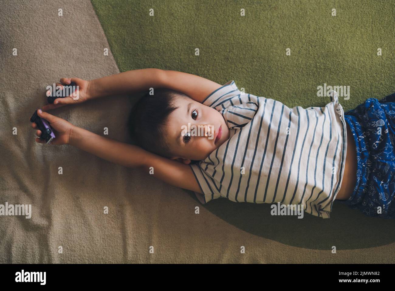 Top view of a boy lying on his back on the bed looking sleepily into ...