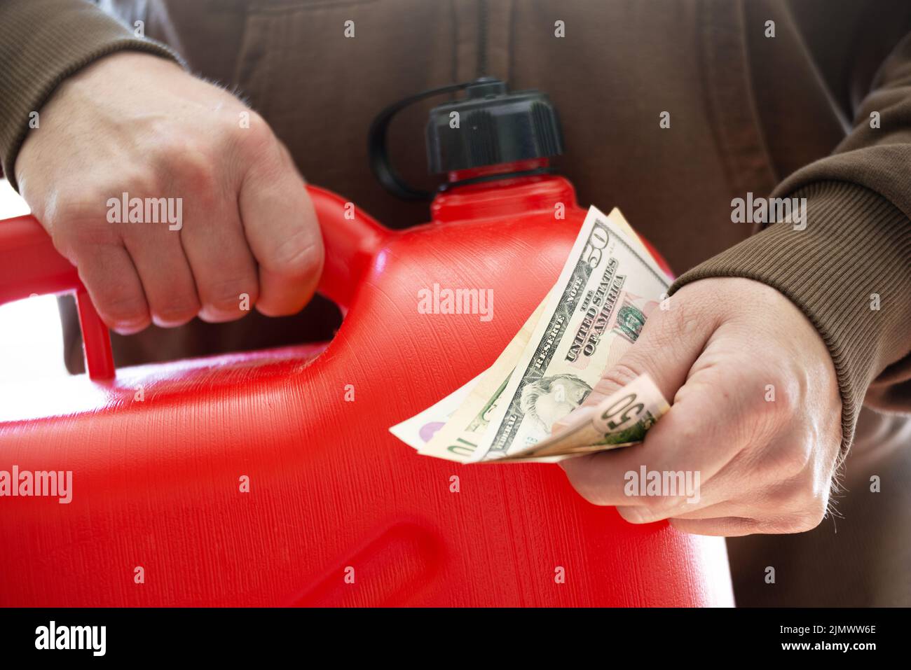 Man holds red jerry fuel can and dollar bills Stock Photo - Alamy