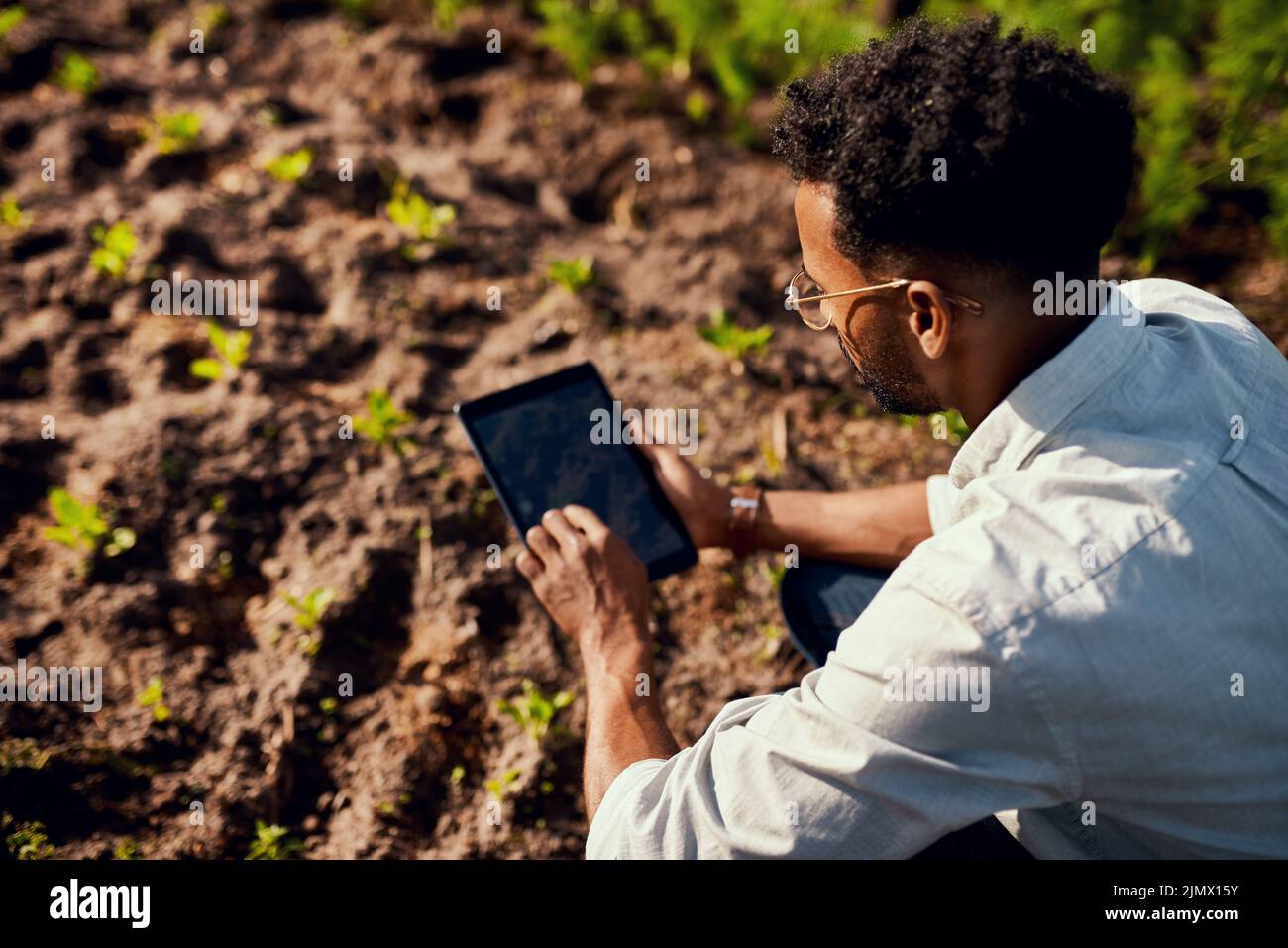 Using technology to check the soil. a handsome young male farmer using ...