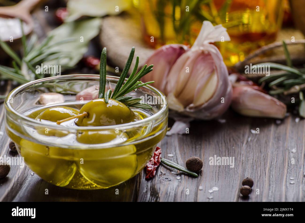Closeup view of green olives oils and spices on kitchen table. Cooking ...