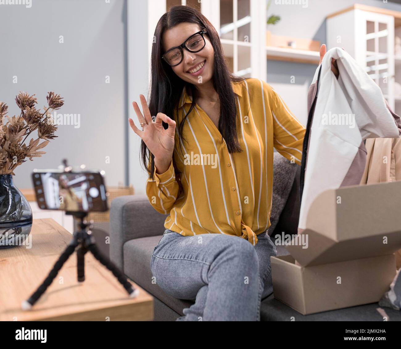 Vlogger home unboxing clothes with smartphone Stock Photo - Alamy