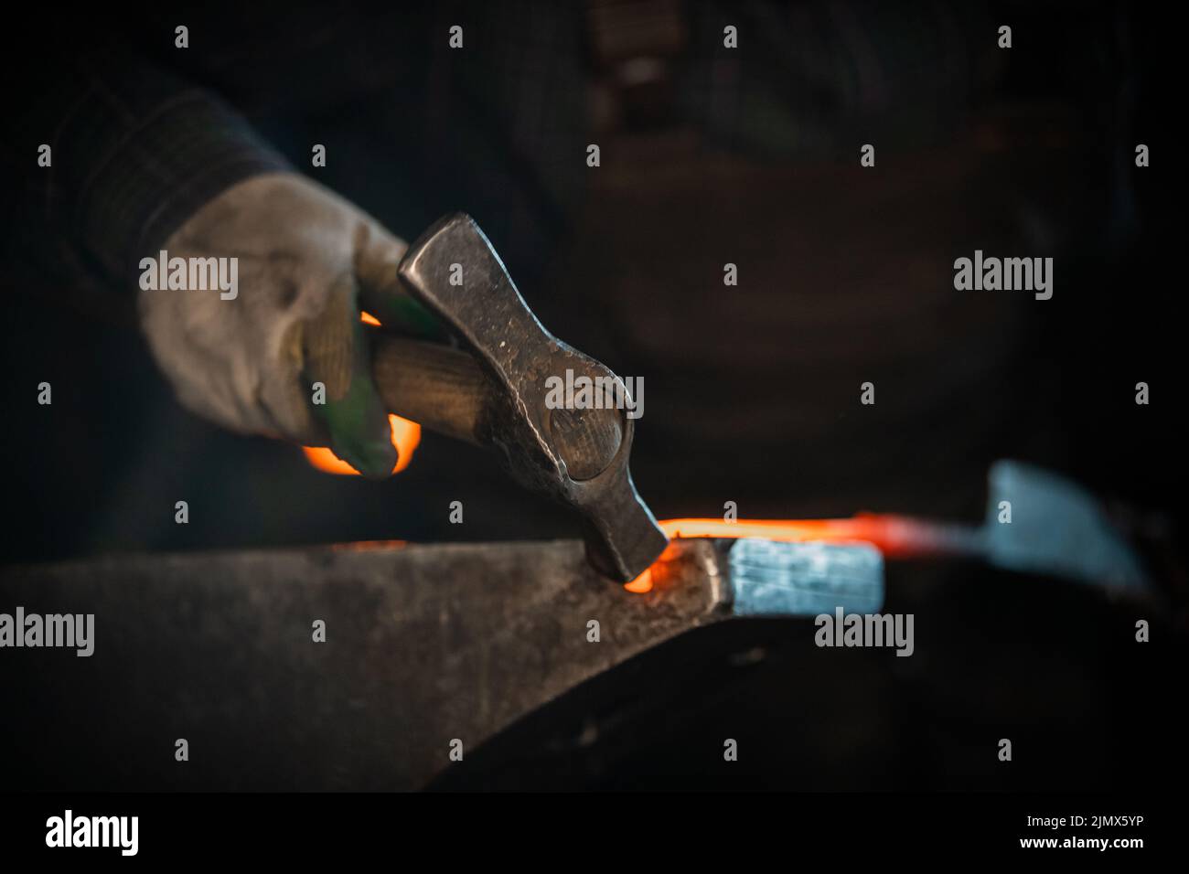 Blacksmith forging a knife out of the hot metal using a hammer ...