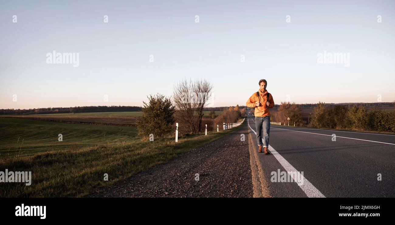 Front view man walking road alone Stock Photo - Alamy