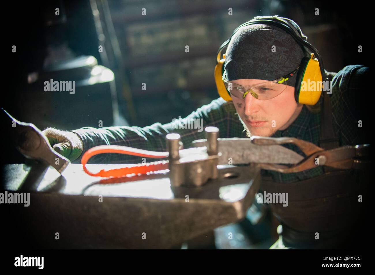 A man blacksmith in protective glasses making a unique handle - bending ...