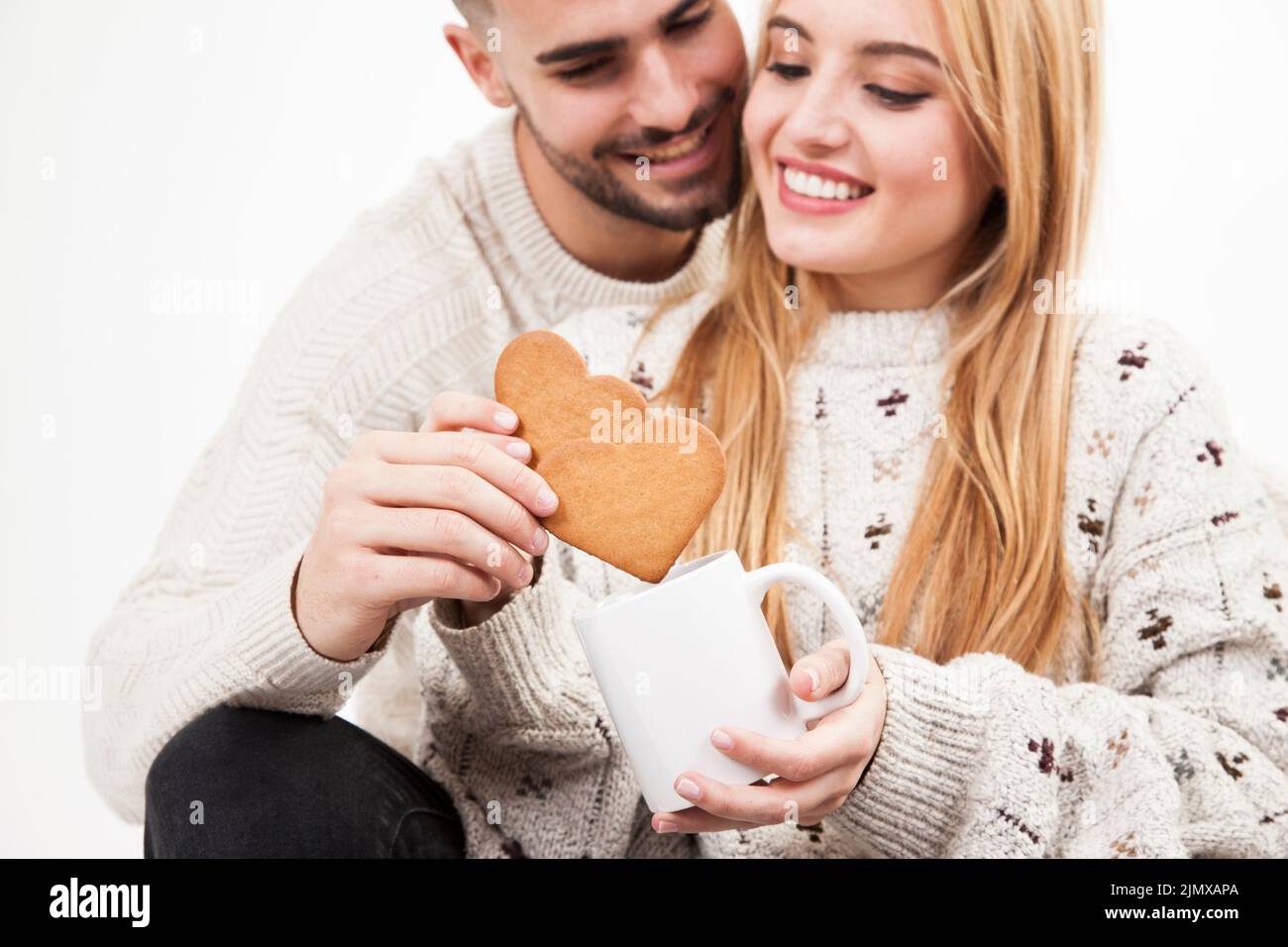 Couple dipping cookies into mug Stock Photo - Alamy