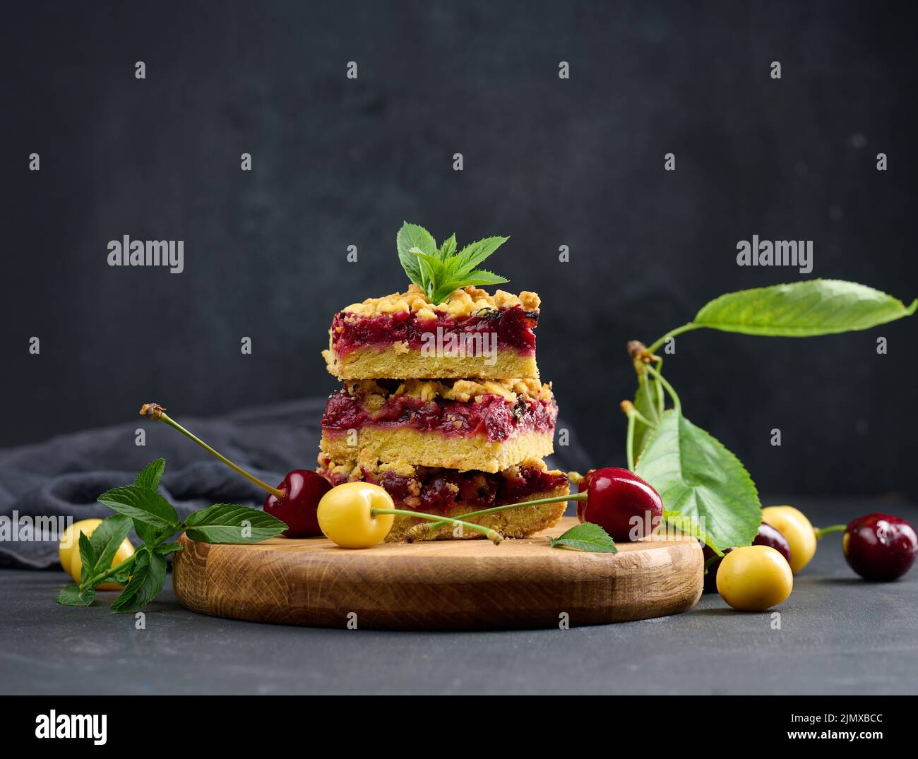 Square slices of cherry crumble lie in a stack on a black board Stock ...