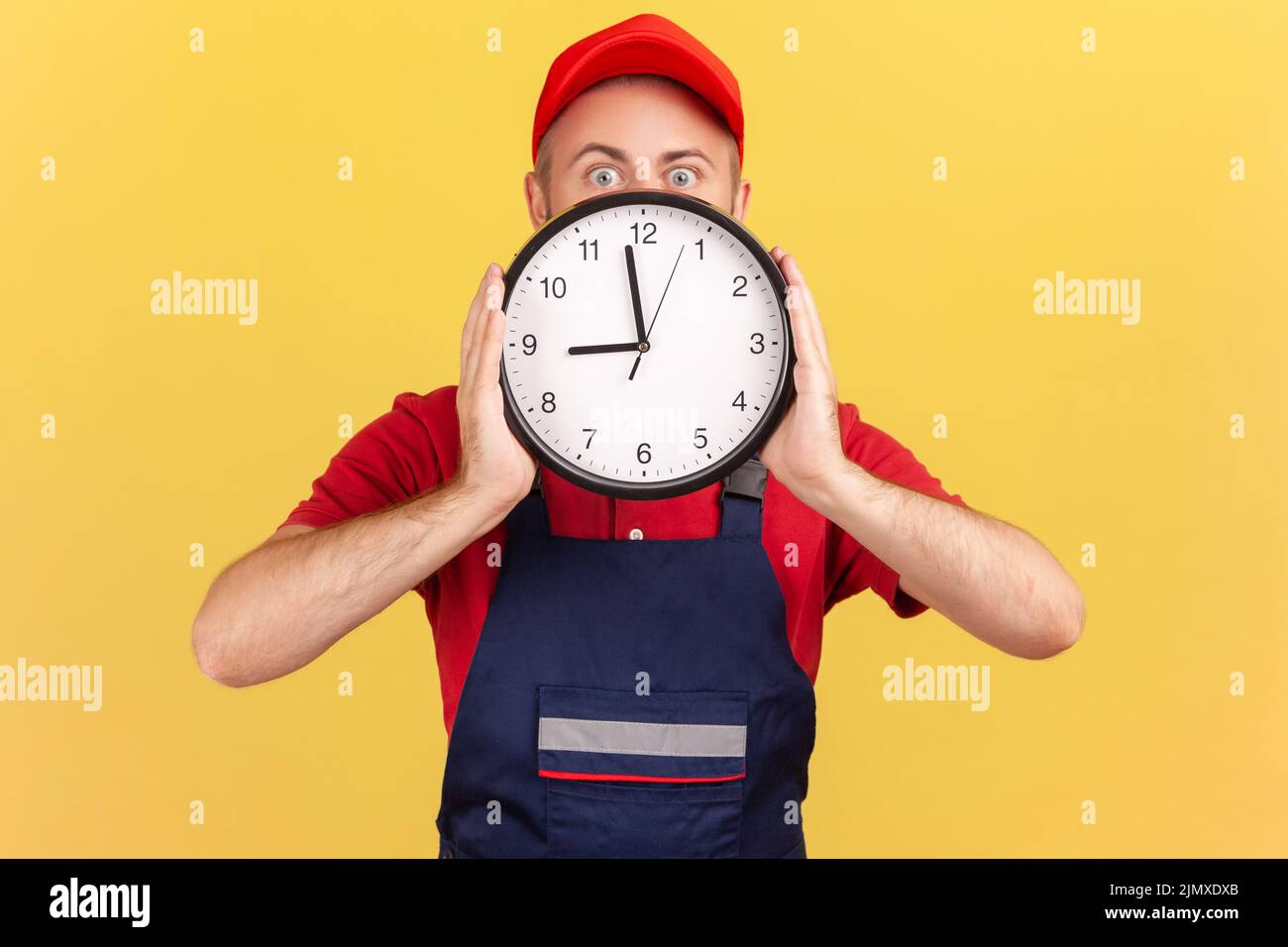 Unknown worker man covering half of face behind big wall clock, the ...