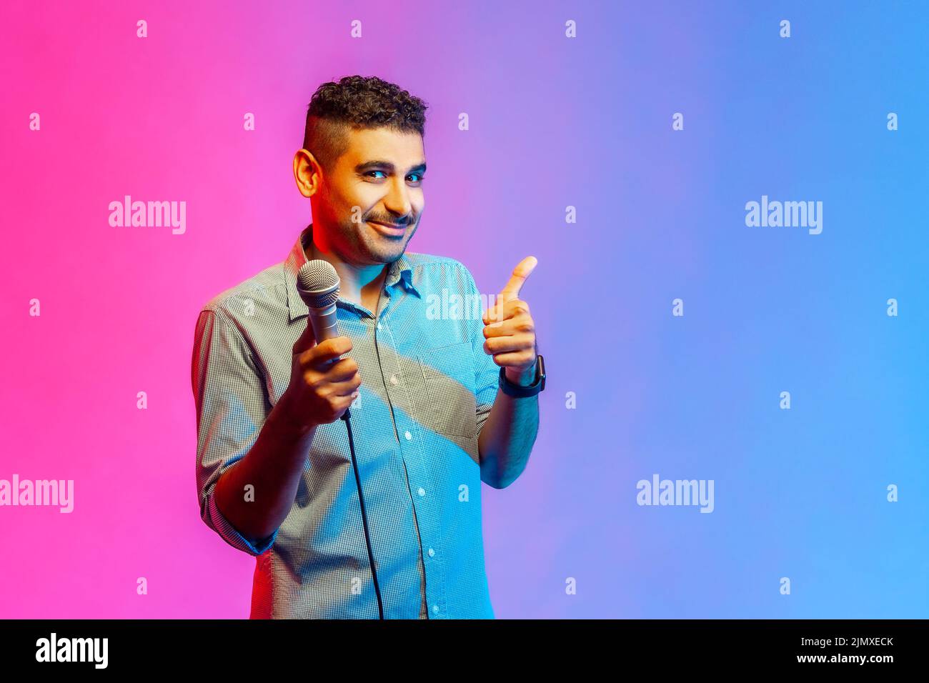 Portrait of attractive man in shirt posing with microphone in hands ...