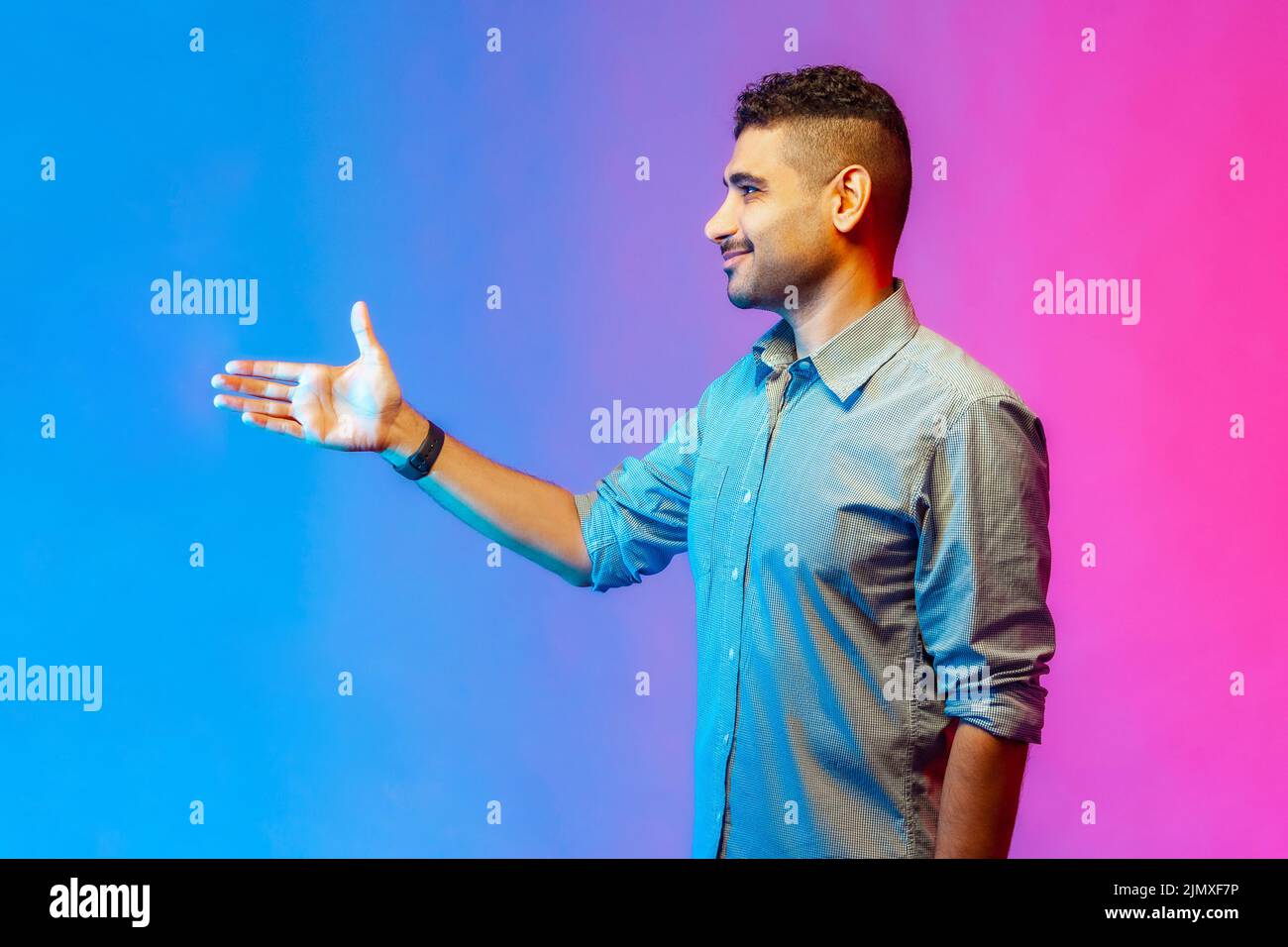 Portrait of happy man in shirt stretching hand welcoming guests with ...