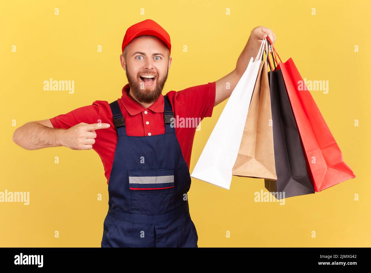 Portrait of cheerful positive delivery man in uniform pointing finger ...
