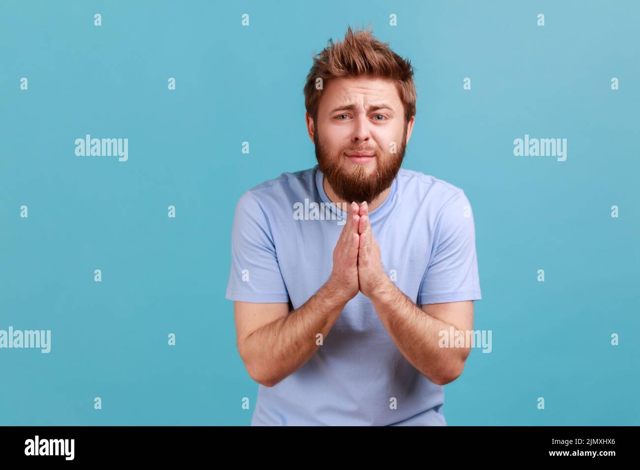 Please, I'm begging. Portrait of bearded man holding arms in prayer ...