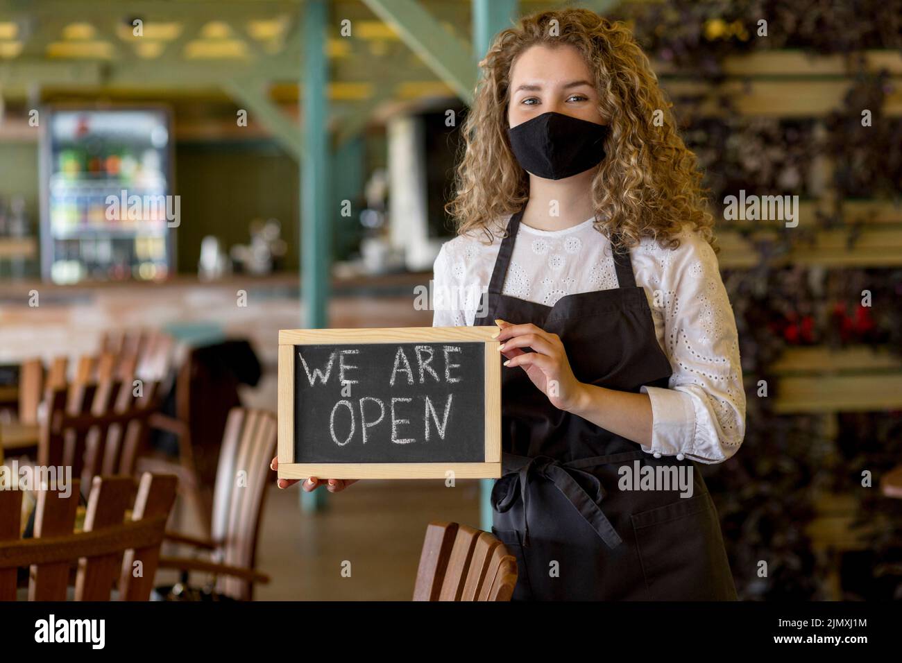 Woman with mask holding chalkboard with open sign Stock Photo - Alamy