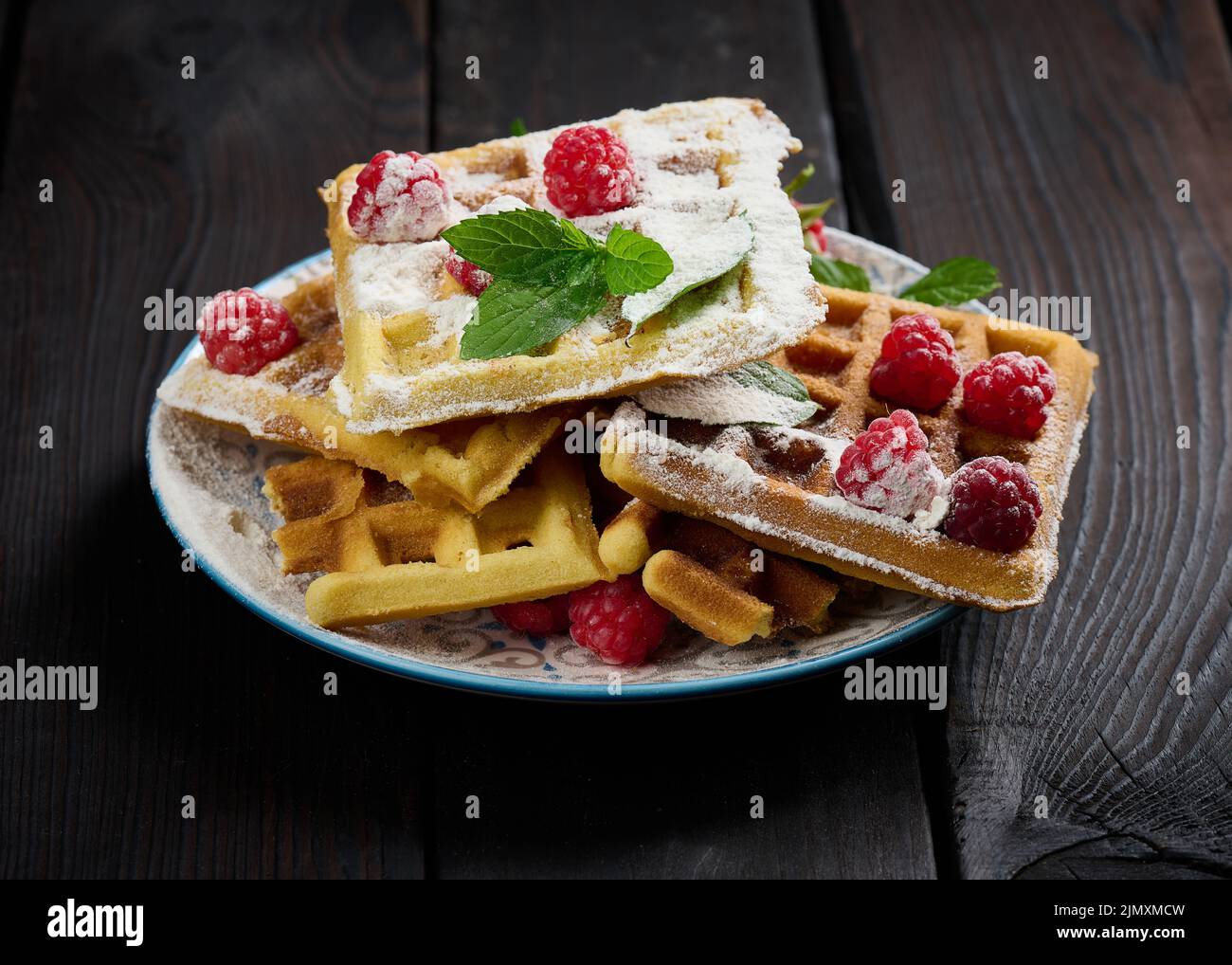 Stack of baked Belgian waffles with ripe red raspberry sprinkled with ...