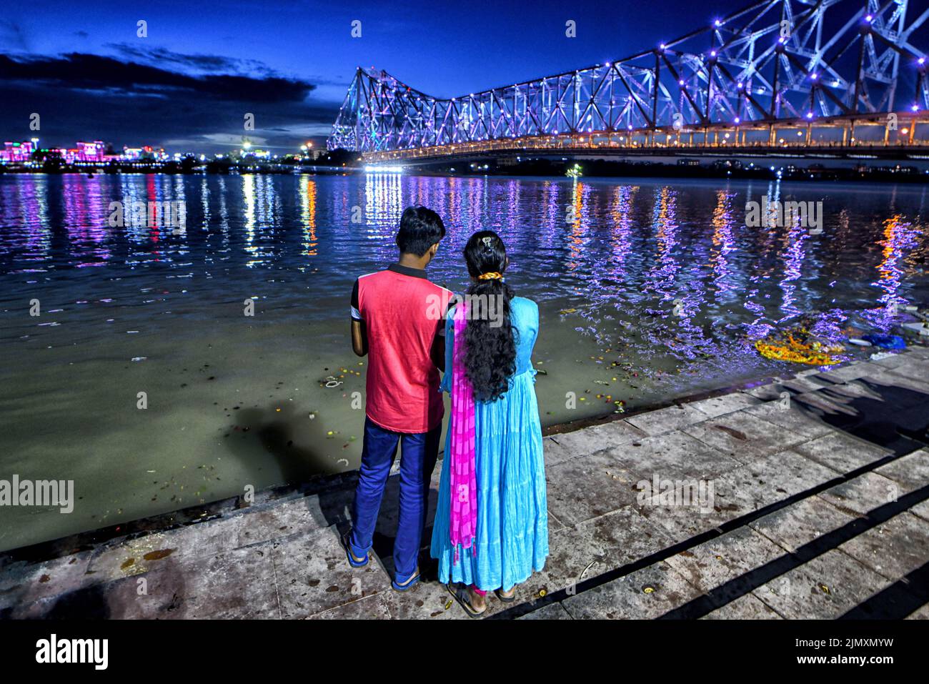 A couple looks at the Howrah Bridge as it has been illuminated in the ...