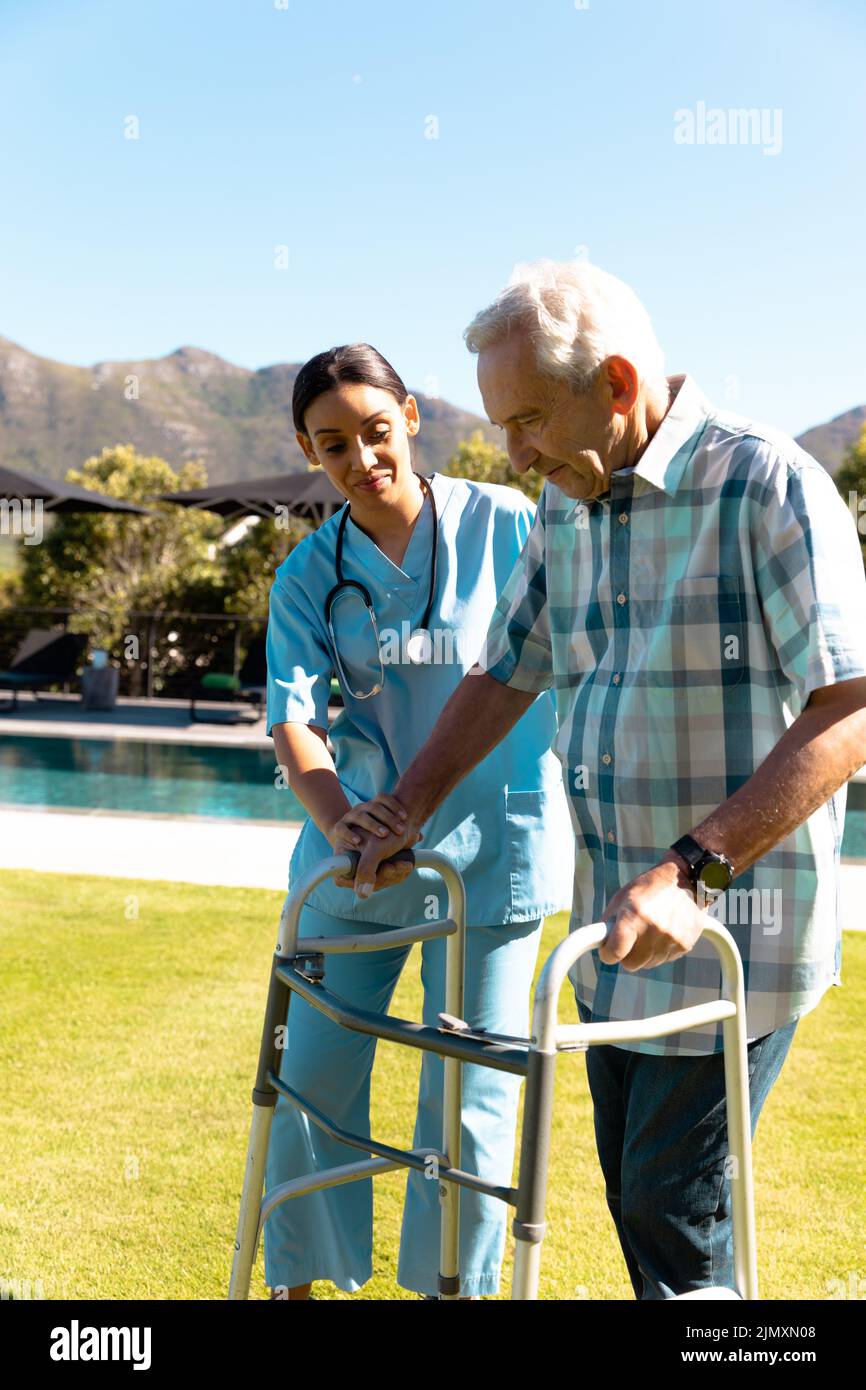 Biracial female health worker helping caucasian senior man to walk with ...