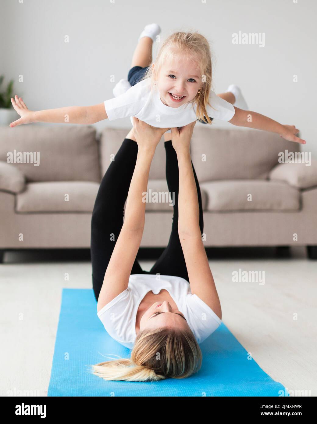 Front view mother exercising with happy child home Stock Photo - Alamy