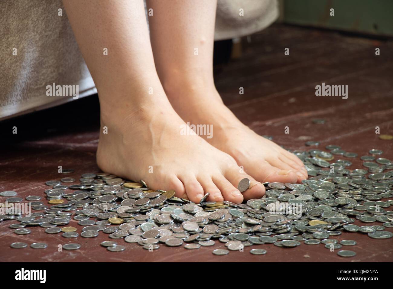 female feet stand on Ukrainian small coins on the floor of the house ...