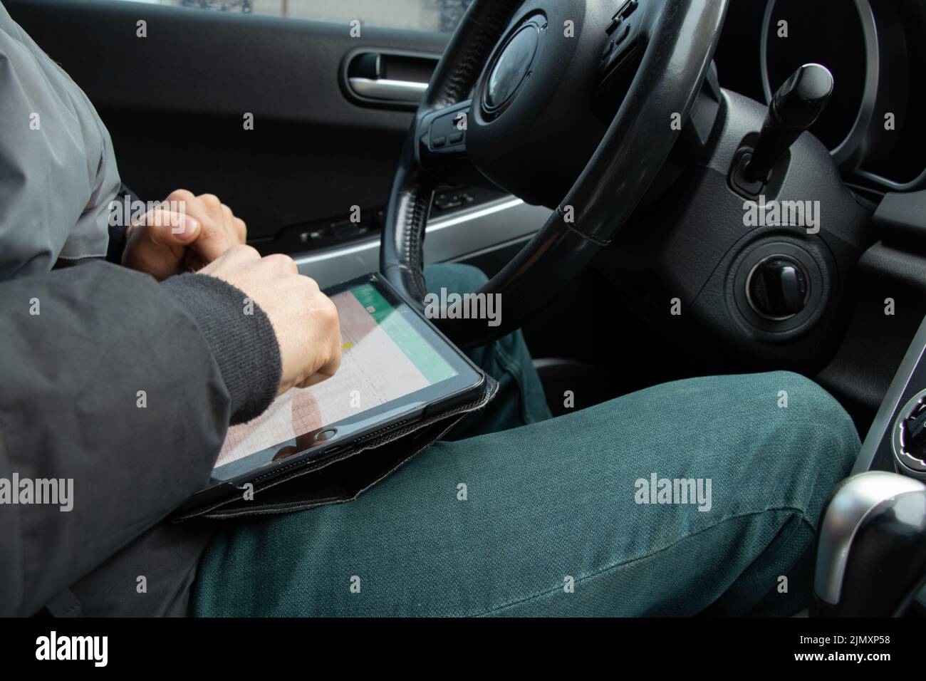 sales representative driving his car with a tablet in his hands, hands ...
