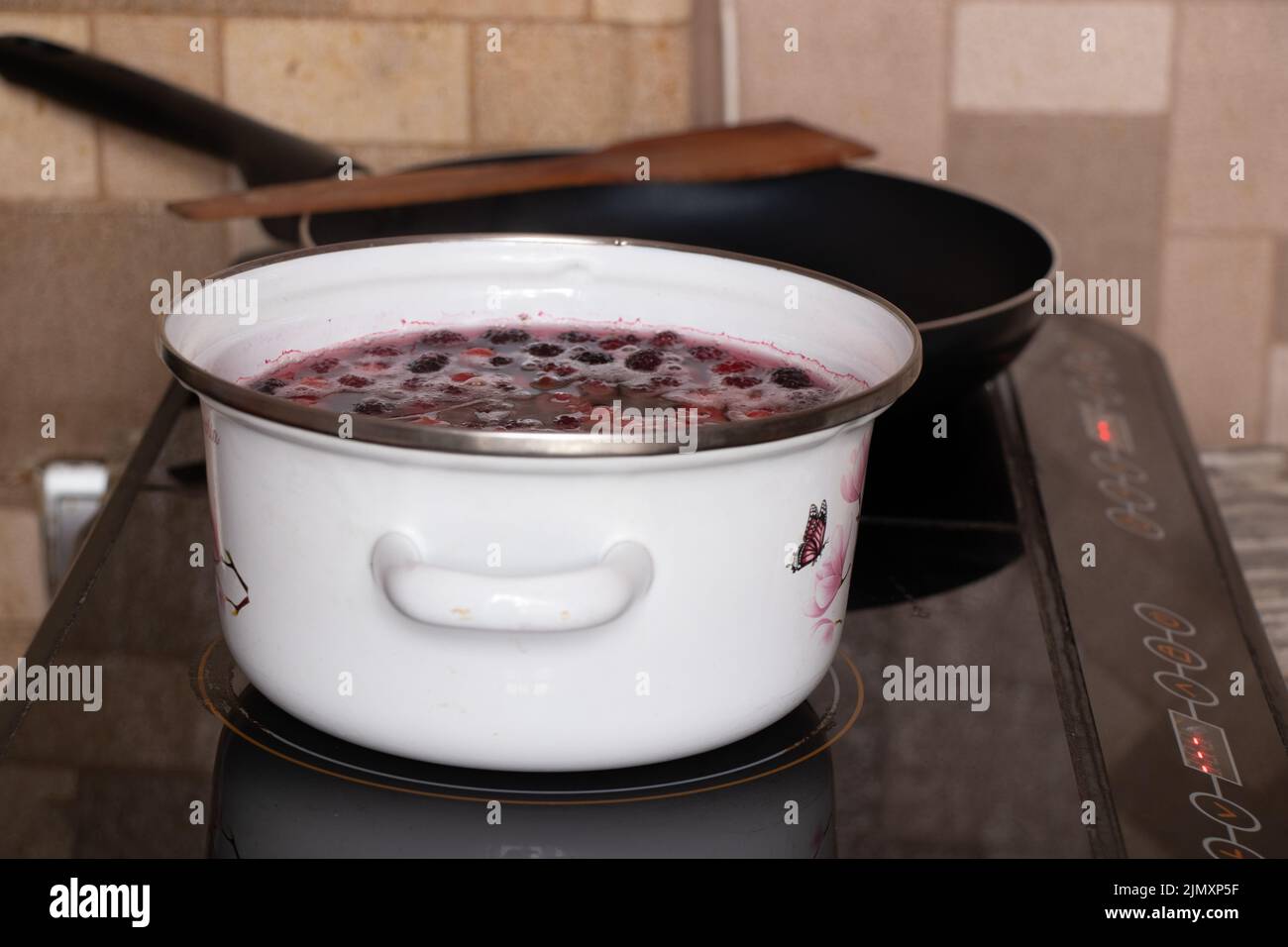 homemade fruit compote with cherry boils on the stove in the kitchen in ...