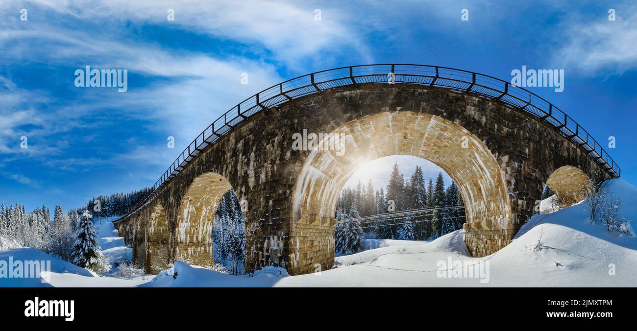Stone viaduct (arch bridge) on railway through mountain snowy fir ...