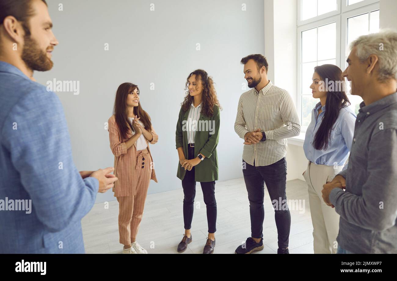 Happy young woman talking to group of people who came to her business ...