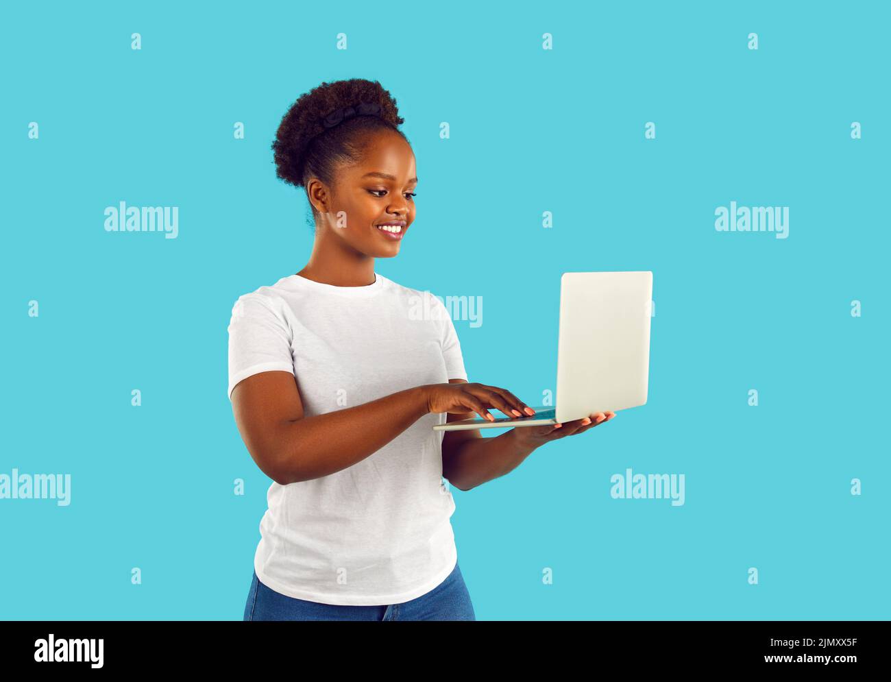 Happy young dark skinned woman smiling typing on laptop isolated on ...