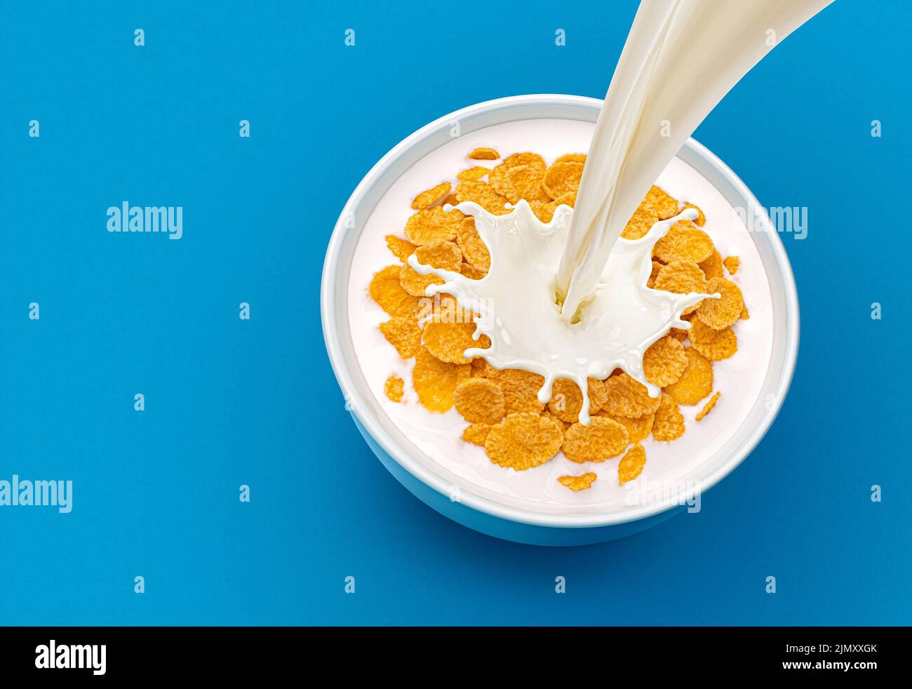 Corn flakes with pouring milk on blue background, top view Stock Photo ...