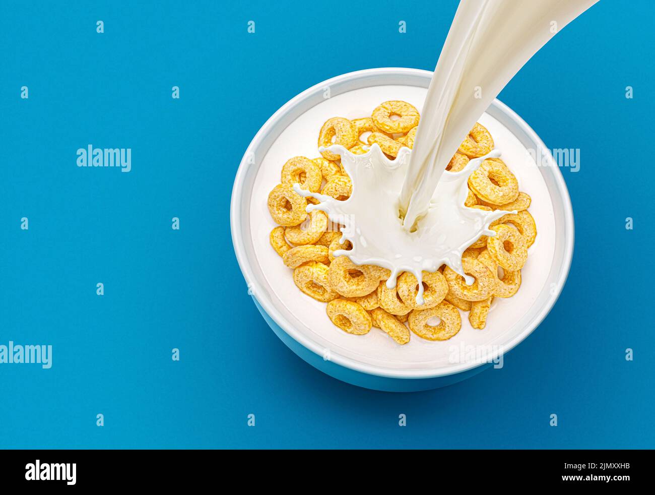 Corn rings with pouring milk on blue background, top view Stock Photo ...