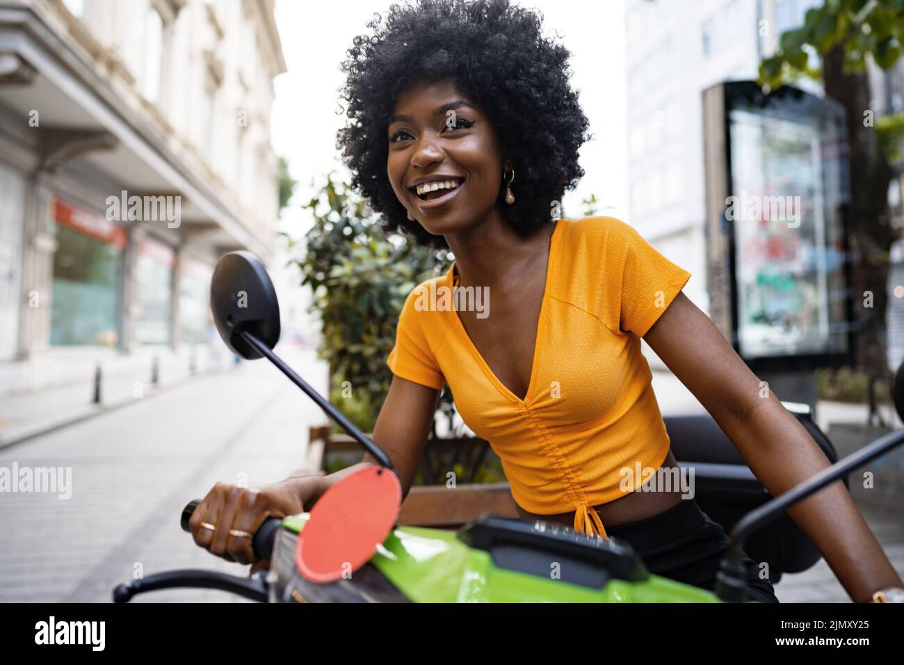 Portrait of young african american woman riding green motorbike in the ...
