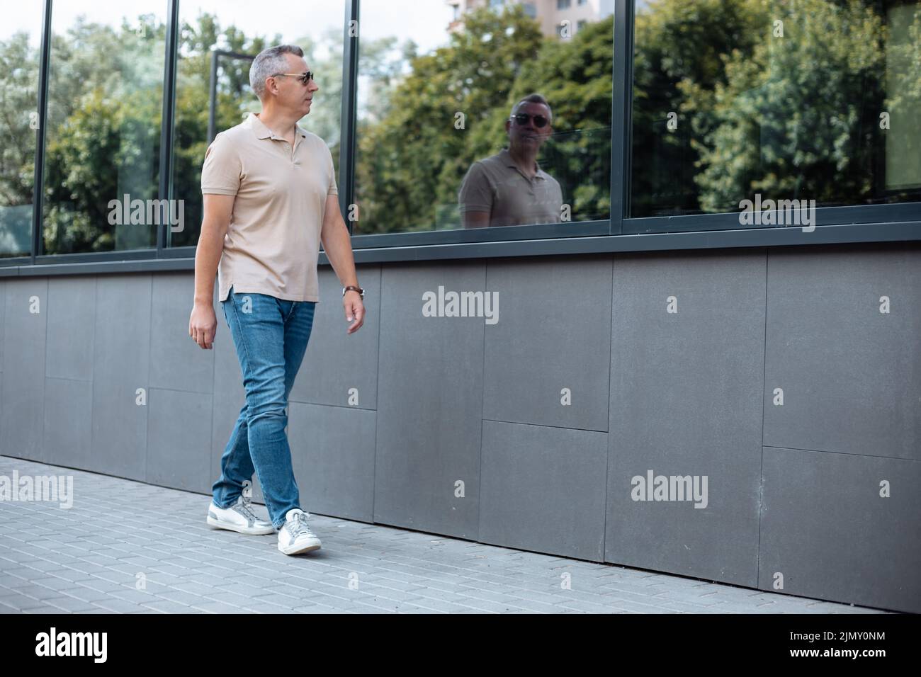 Portrait side view from below of old man in sunglasses walking on ...