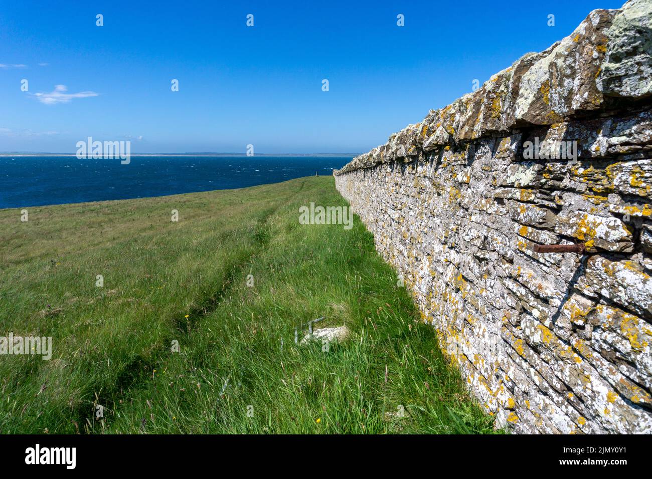 Traditional stone and rock wall separating green grassy fields on the ...