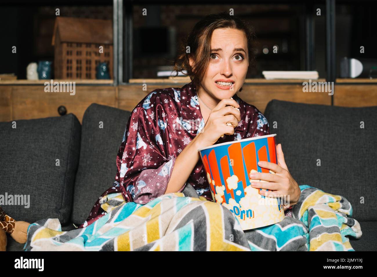 Scared young woman watching television Stock Photo - Alamy