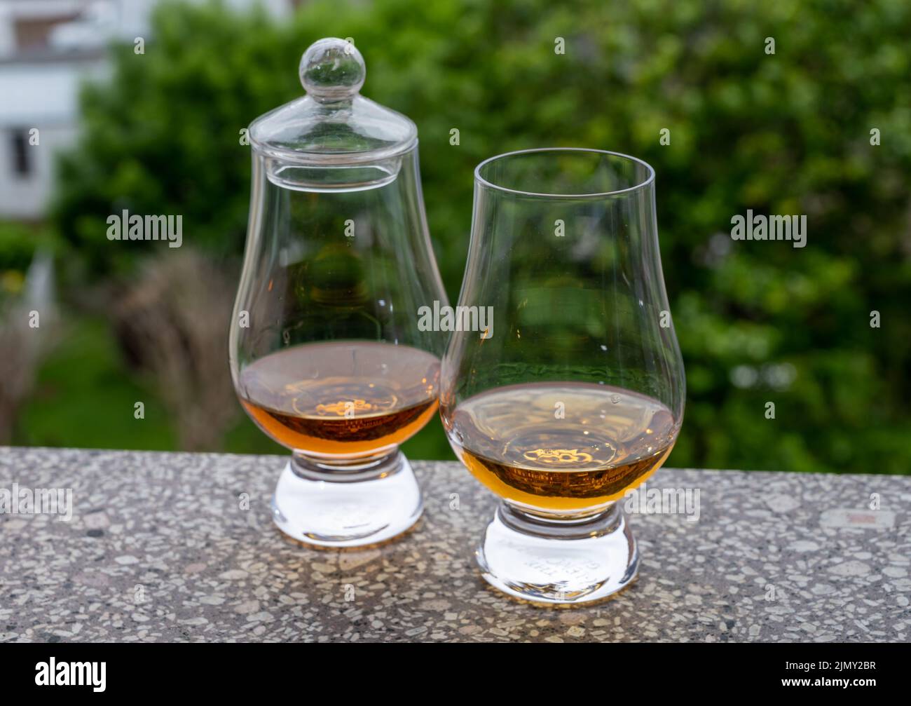 Two drams of scotch whiskey with view on old houses on background ...