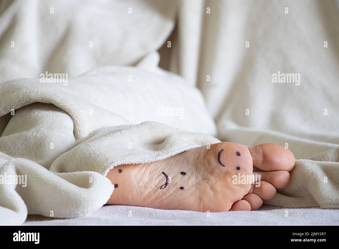 a smile and sad emoticons are drawn on the girl s leg, legs on the bed ...