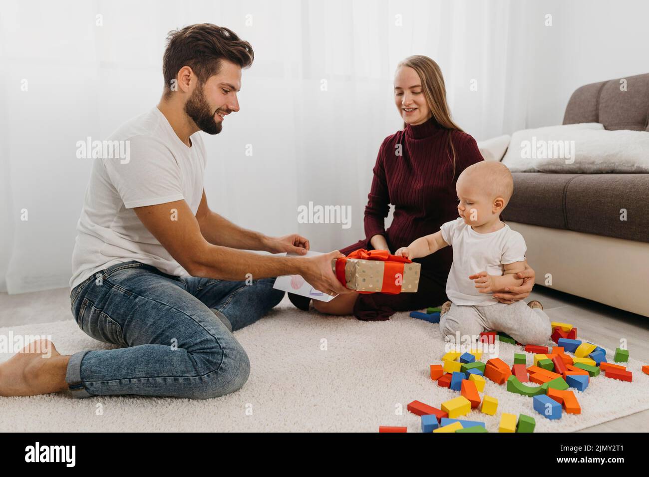 Parents giving gift their baby home Stock Photo - Alamy
