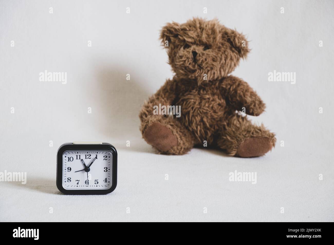 children's teddy bear and a clock on a white background, an alarm clock ...