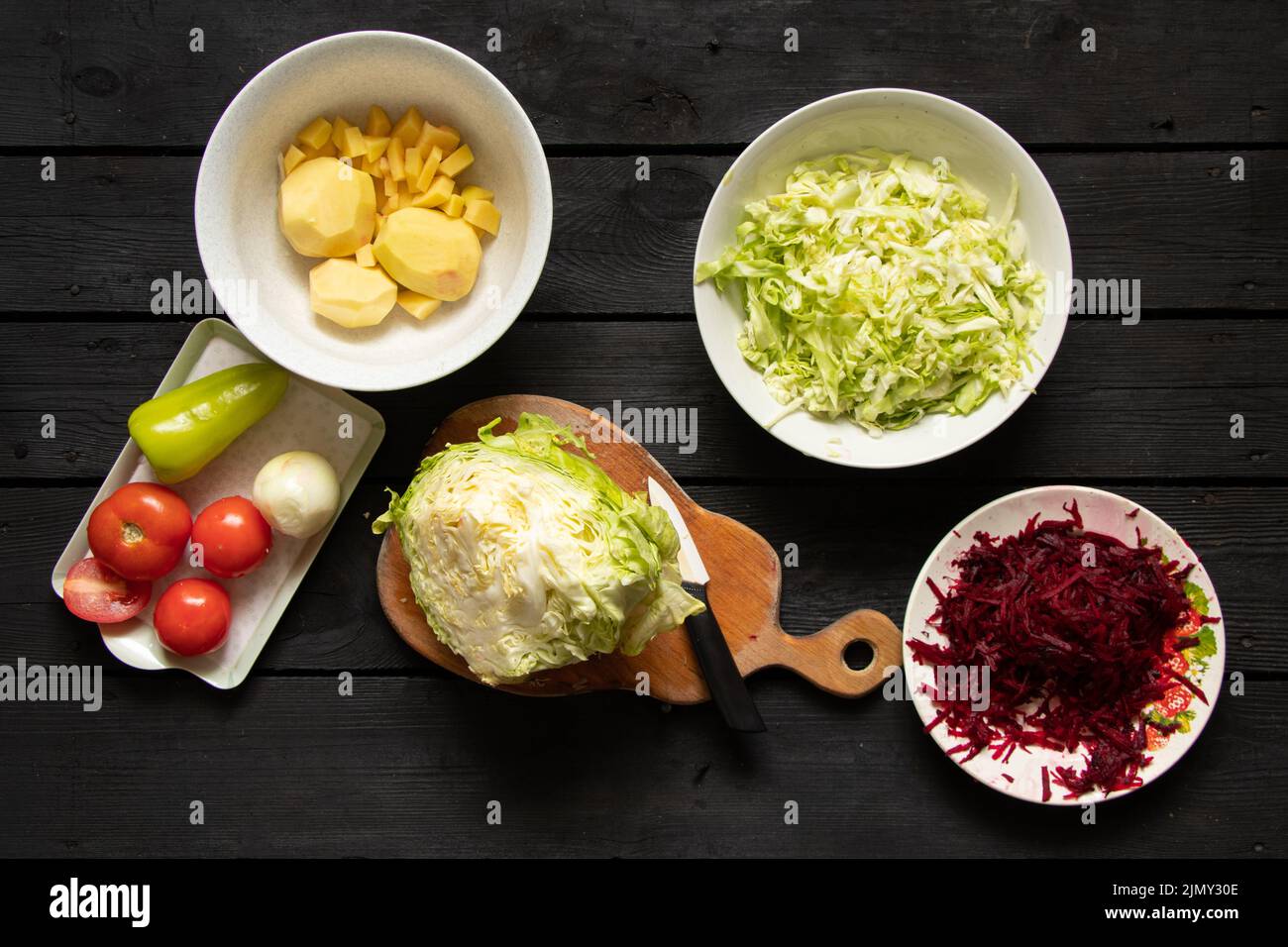 cabbage potatoes pepper tomato beetle are slicing on the table, cooking ...