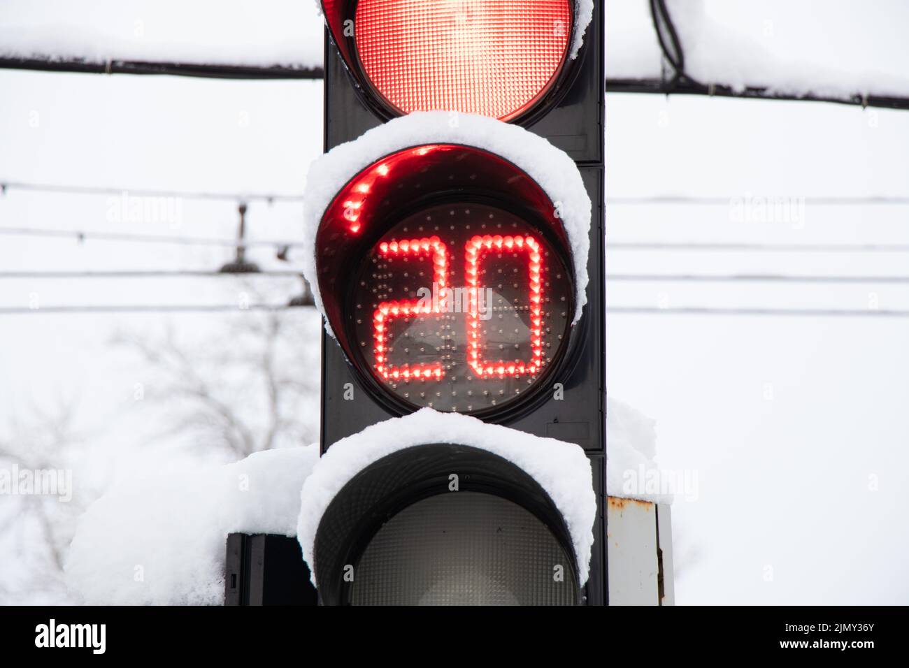 red traffic light on the background of the sky in winter in snow and ...