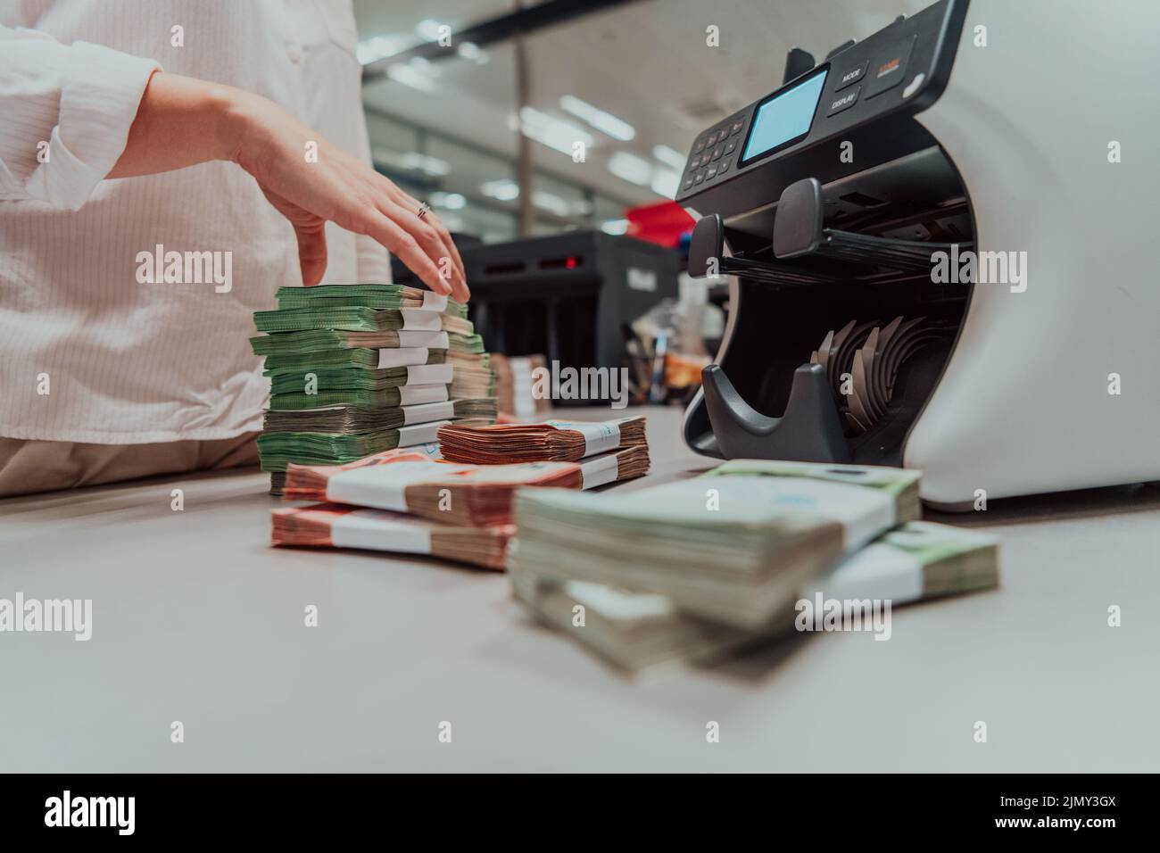 Bank employees using money counting machine while sorting and counting ...