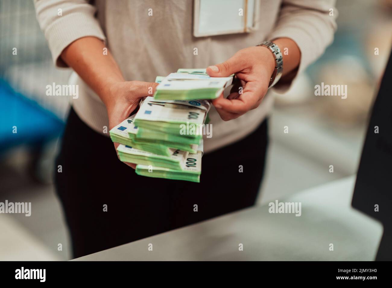 Bank employees holding a pile of paper banknotes while sorting and ...