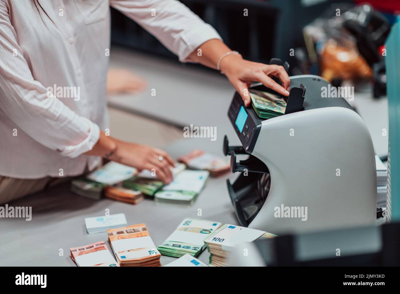 Bank employees using money counting machine while sorting and counting ...