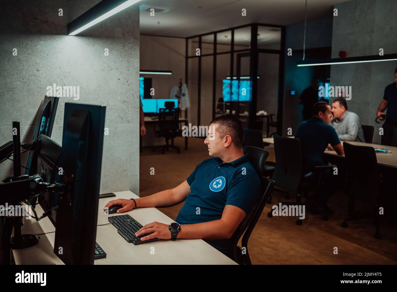 Male security operator working in a data system control room offices ...