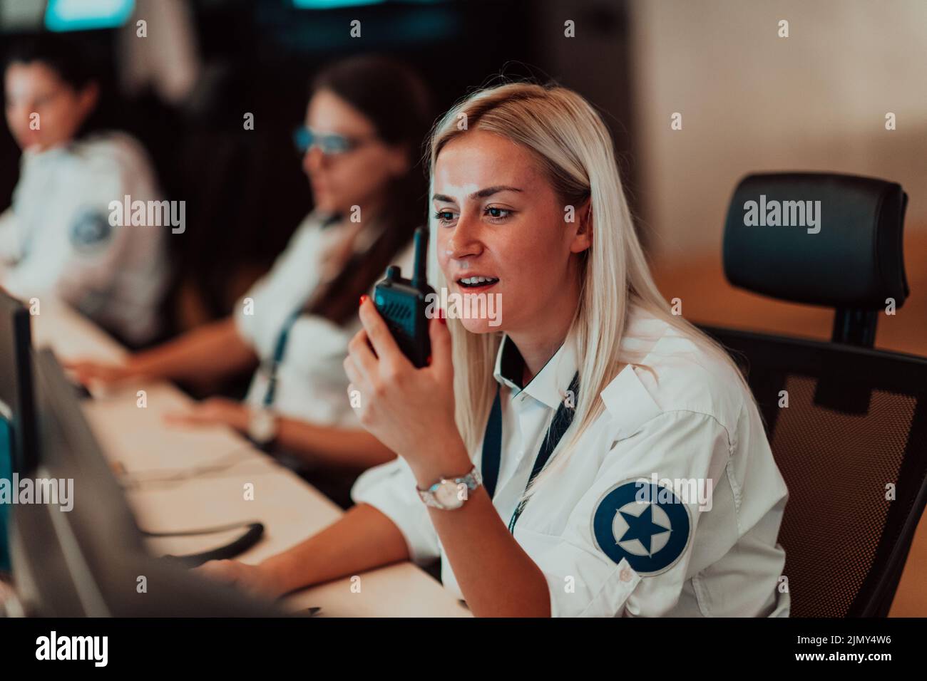 Female security operator holding portable radio in hand while working ...