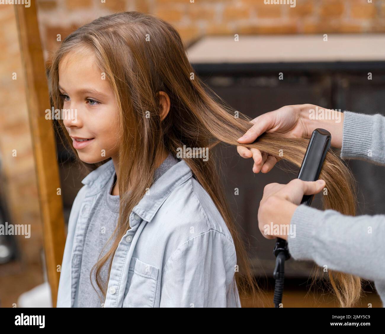 Little girl getting her hair straightened by beautician Stock Photo - Alamy