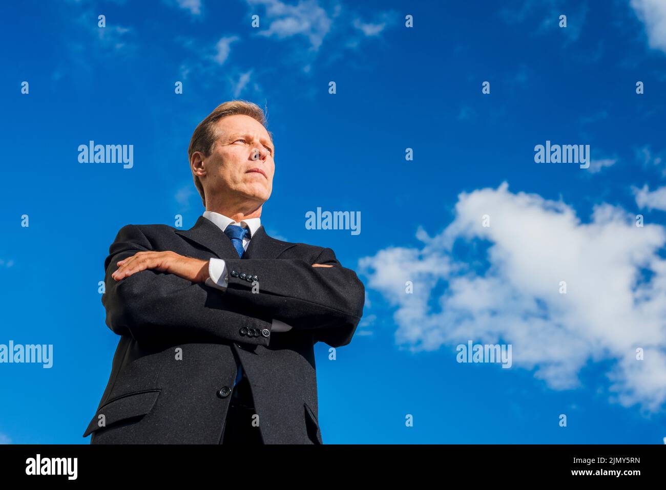Low angle view businessman standing with folded arms against sky Stock ...