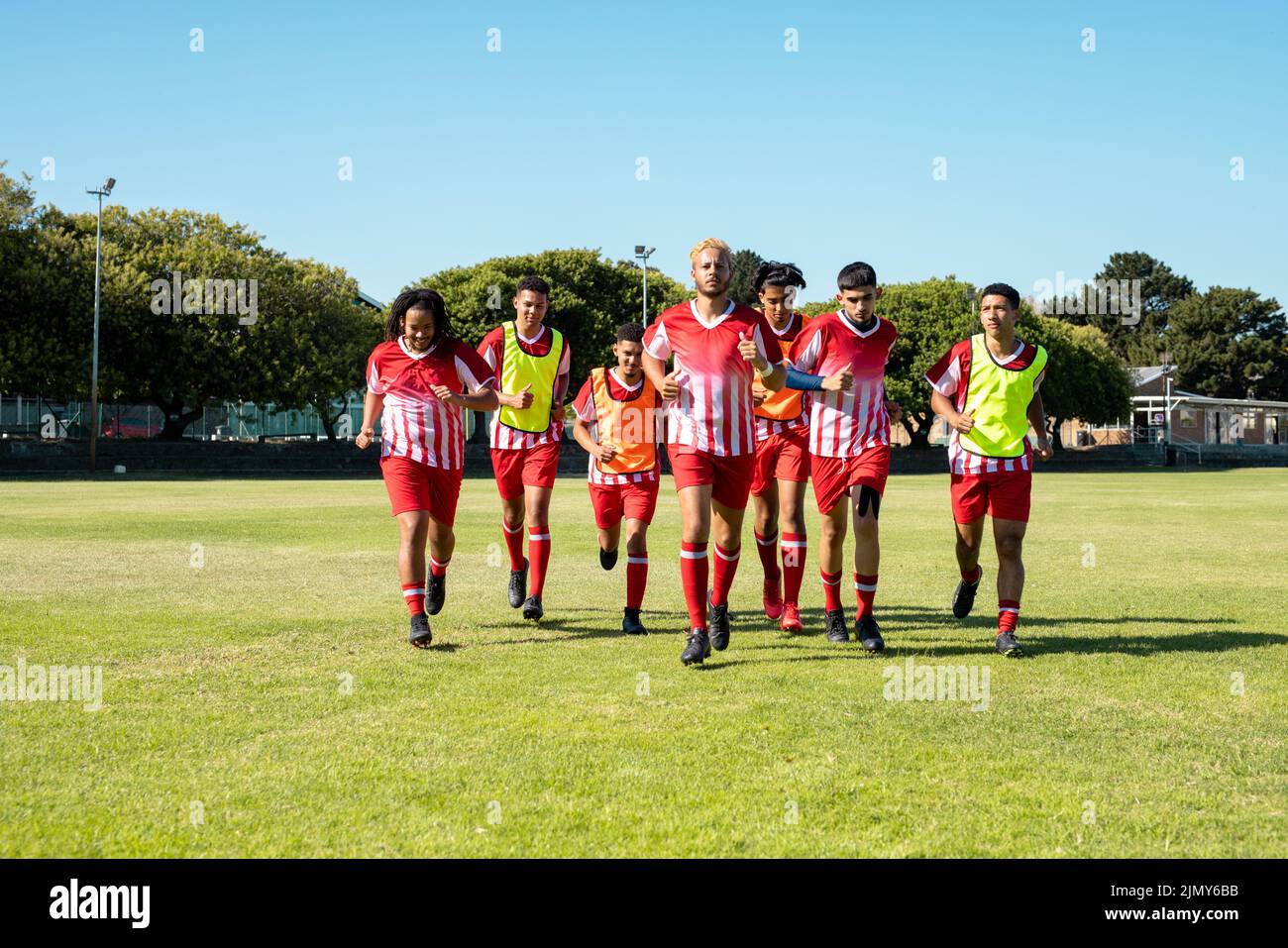 Multiracial male soccer players wearing red sports uniforms running at ...