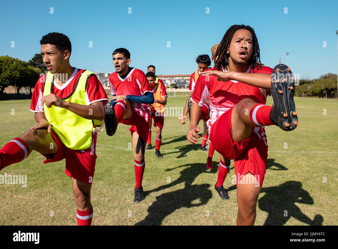 Multiracial male athletes stretching legs while standing on playground ...